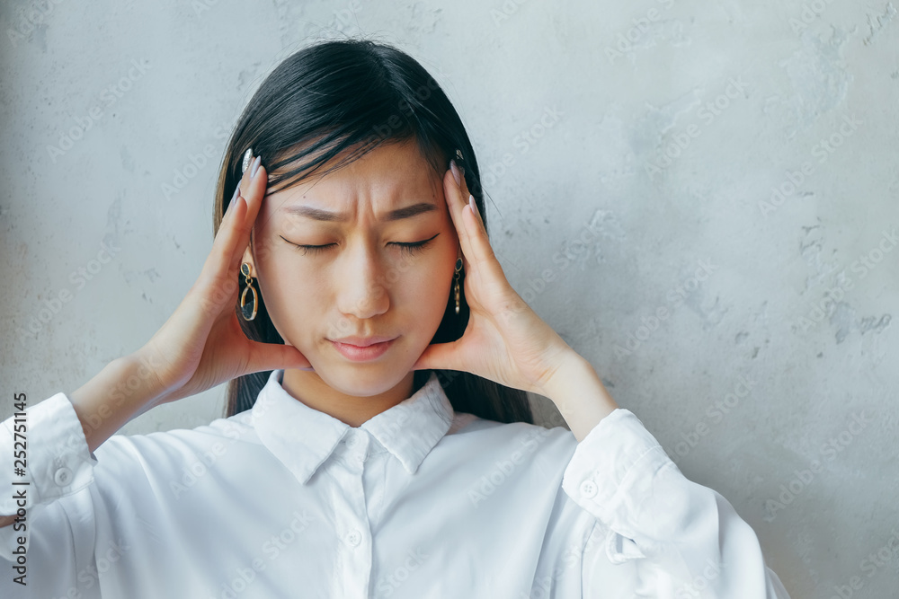 Stressed frustrated Beautifulasian girl in white shirt tensely thinks, holding hands at the ...