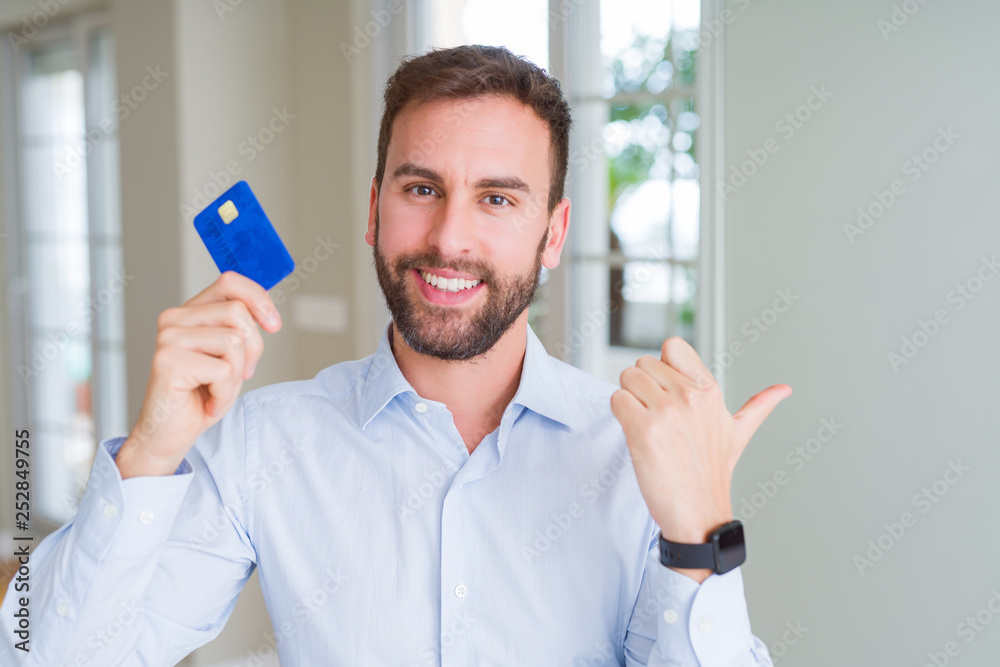 Handsome business man holding credit card pointing and showing with ...