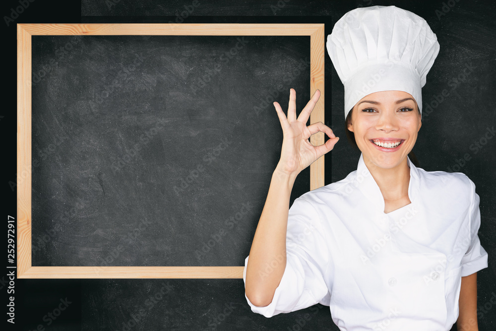 Happy chef doing perfect okay hand sign at empty menu black board ...