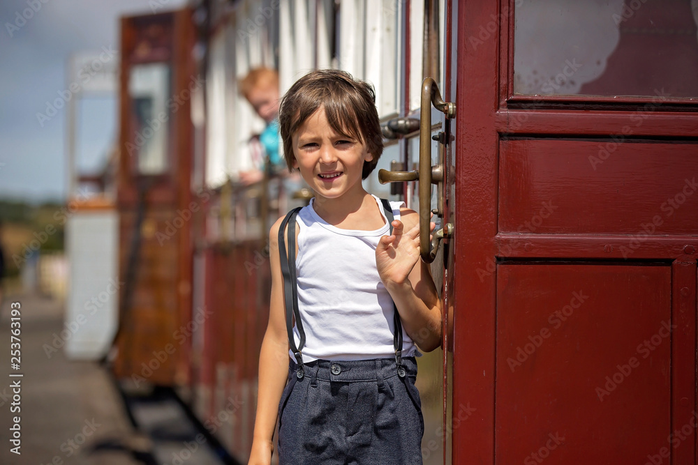 Beautiful child, dressed in vintage clothes, enjoying old steam train ...