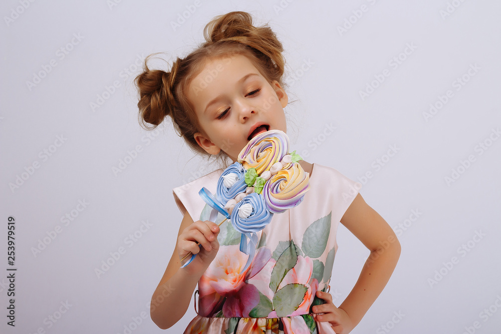 little girl in a pink dress with flowers holding a candy on a stick ...