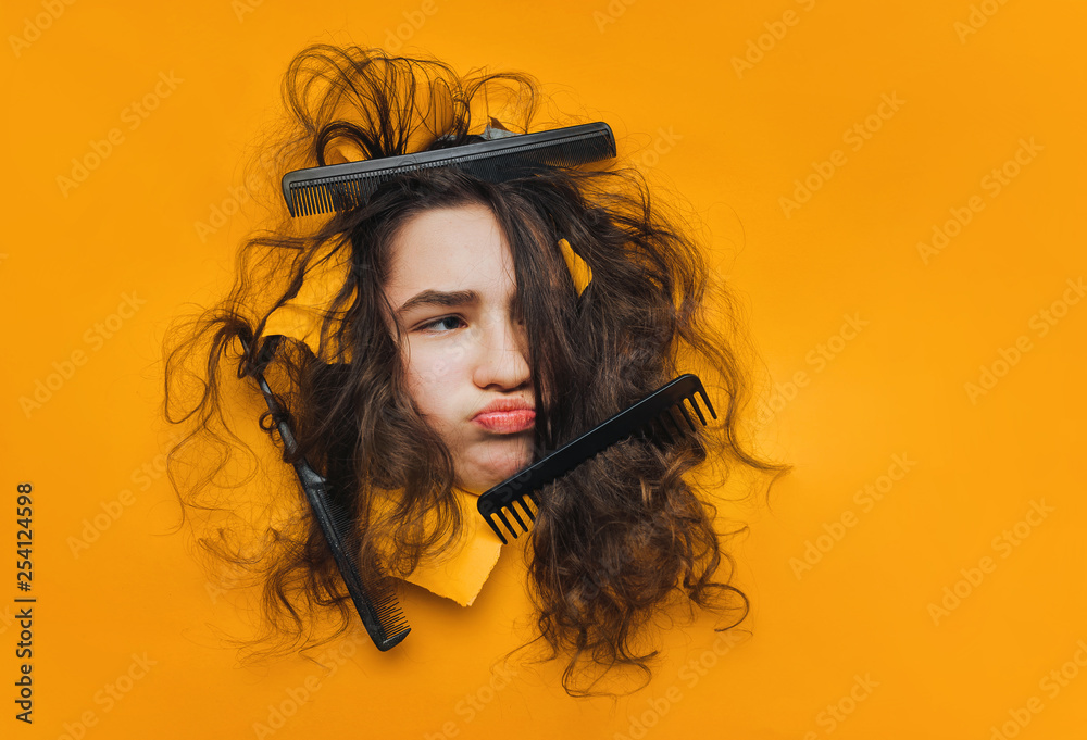 A funny teenage caucasian girl with problematic curly hair expresses ...