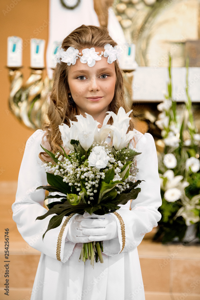 Portrait of cute little girl on white dress and wreath on first holy ...