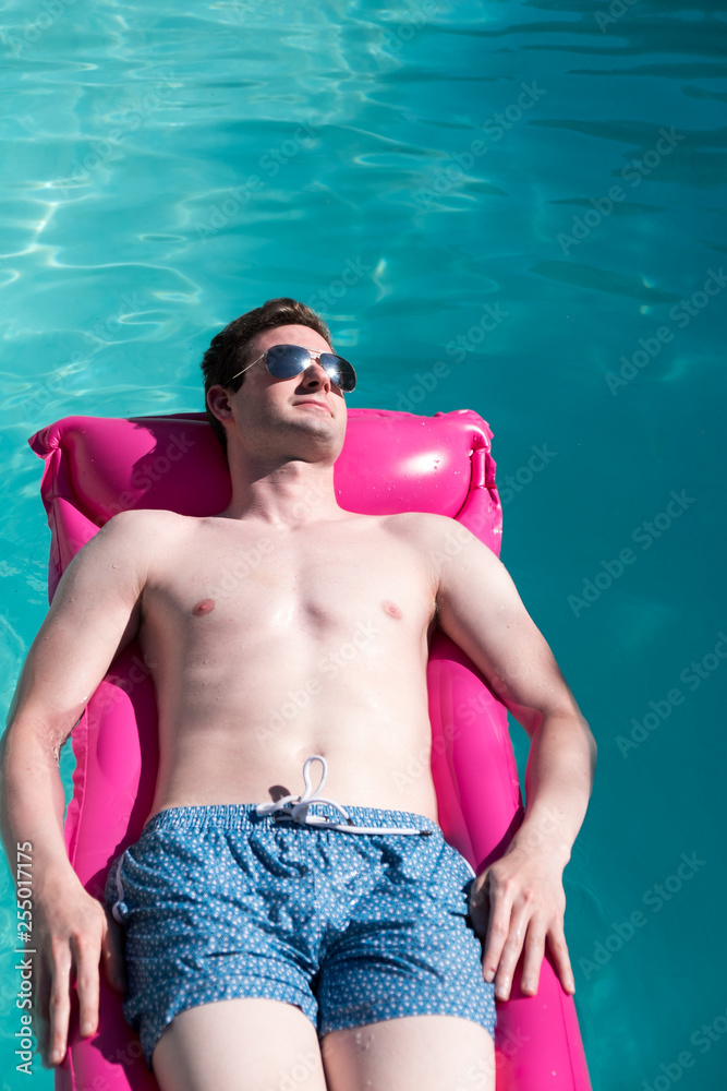 Man in his 20s on vacation relaxing in an outdoor swimming pool in the ...