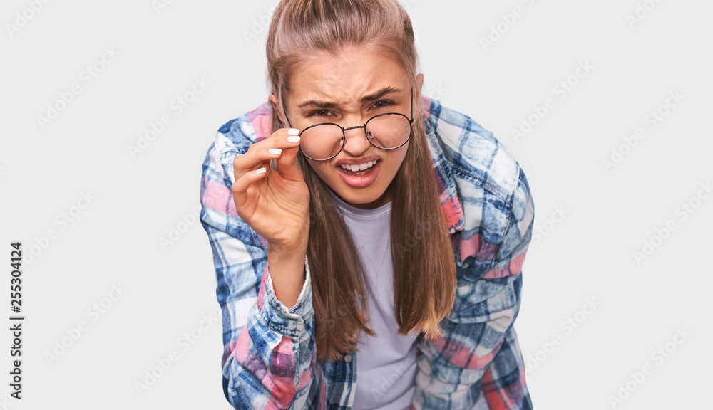 Close up portrait of displeased and questioned young woman taking off ...