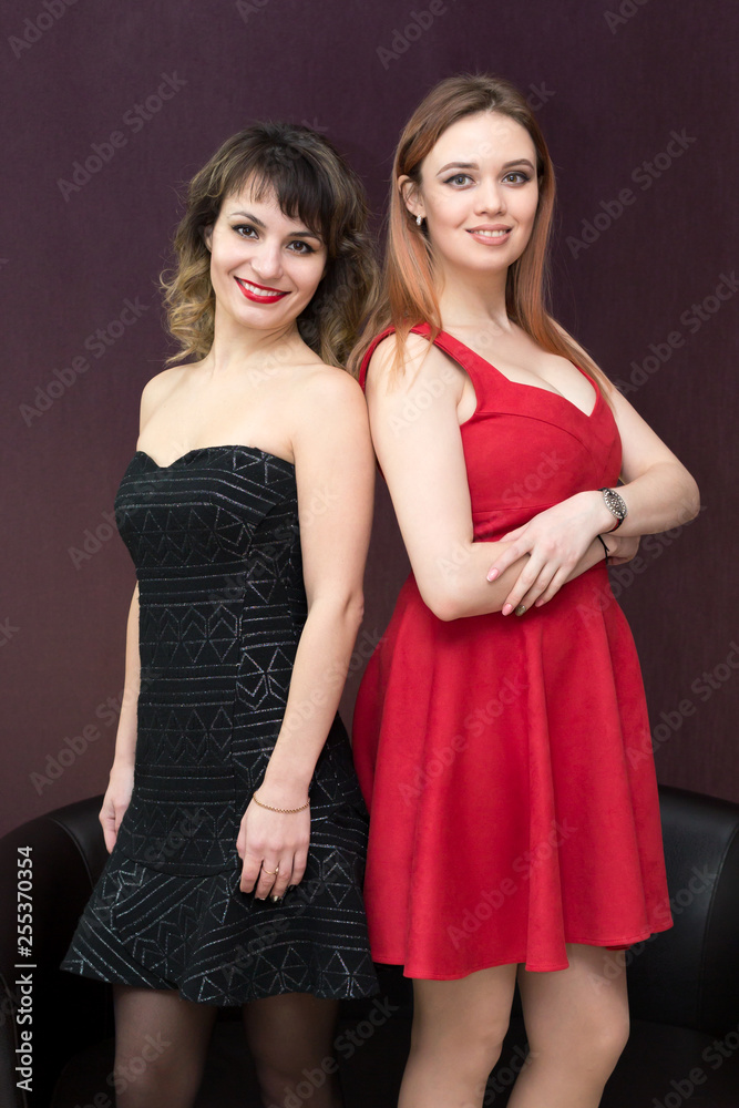 Best friends stand with their backs to each other. Two girls in red and ...