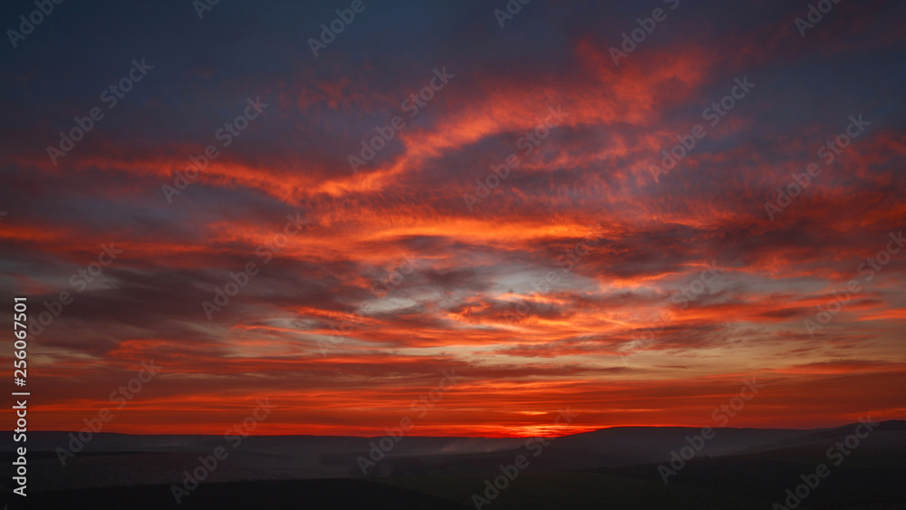 Colorful magnificent sunset in countryside above hills and fields ...
