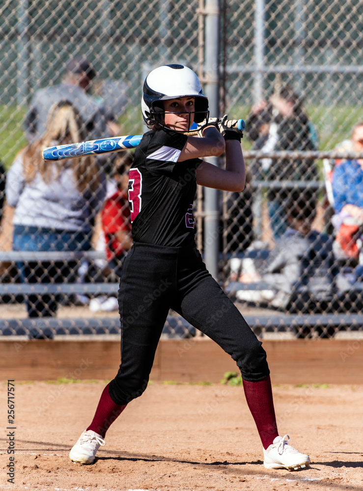 Female softball player in black uniform tracking the flight of her hit ...