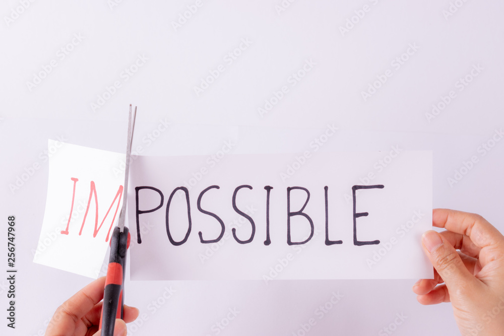Woman using scissors to remove the word IMPOSSIBLE to read POSSIBLE ...