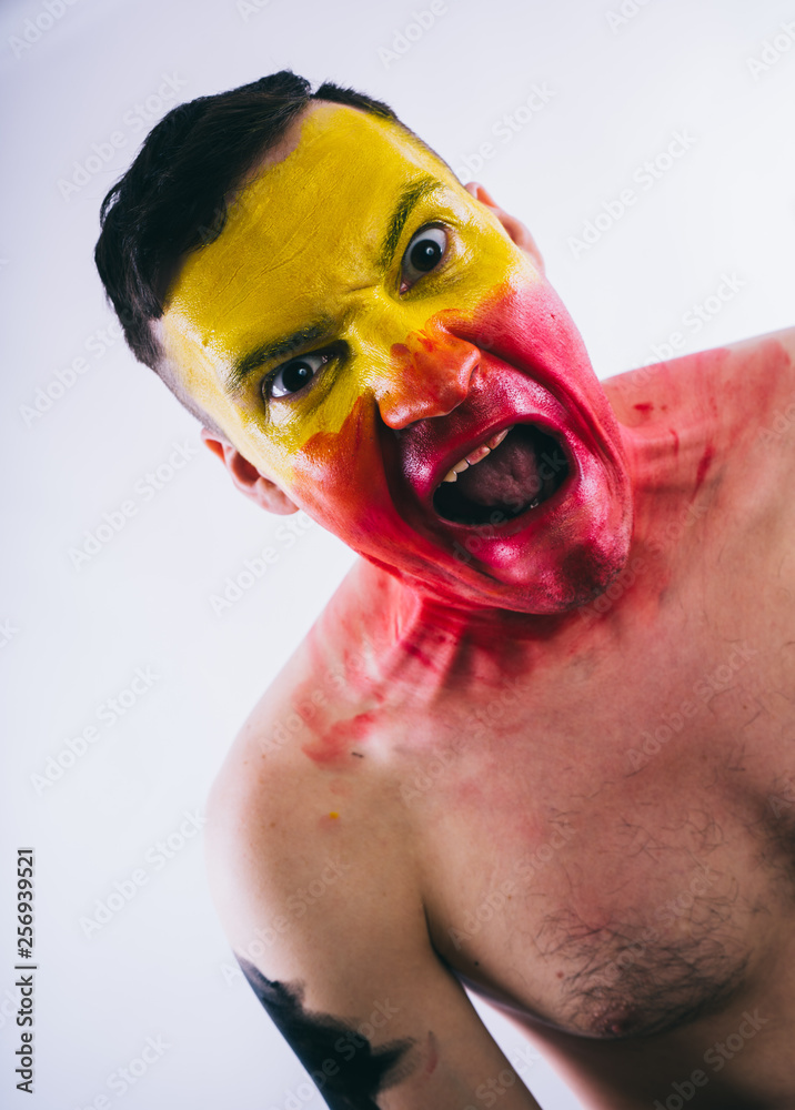 Crazy guy posing with a painted face. A bizarre portrait of a man with ...