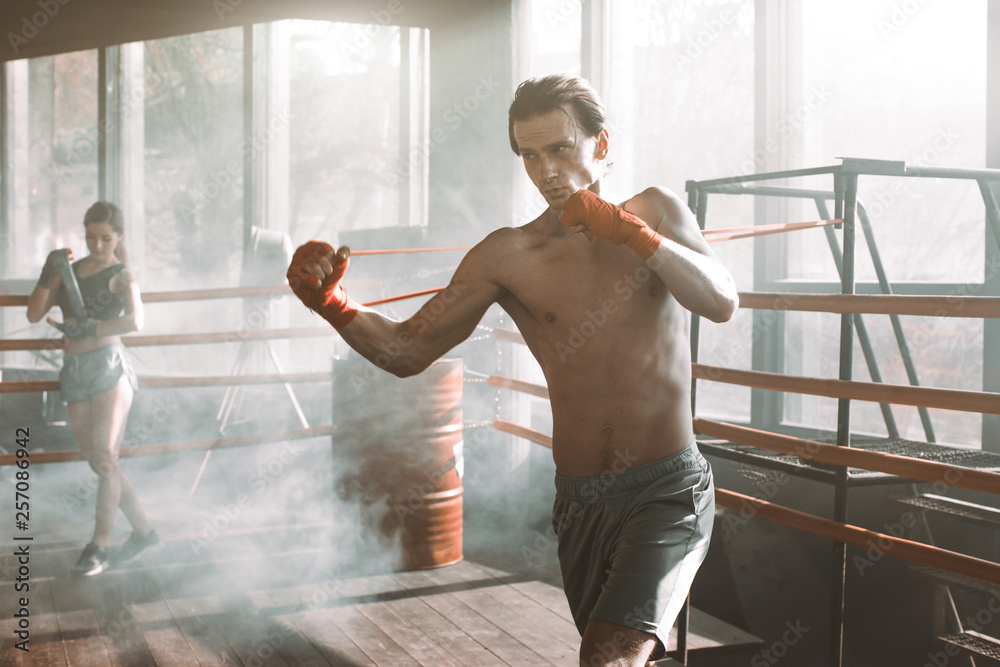 Handsome man working out with resistance band in the boxing ring at the ...