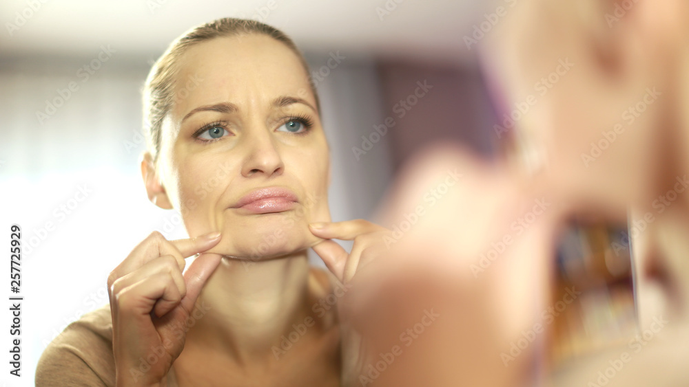 the girl looks in the mirror, dissatisfied with the appearance, pulls ...