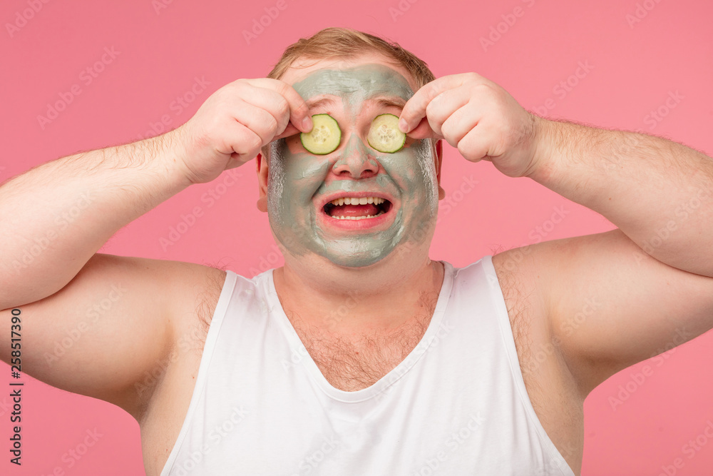 Happy funny tubby man with facial clay mask for skin care having fun ...