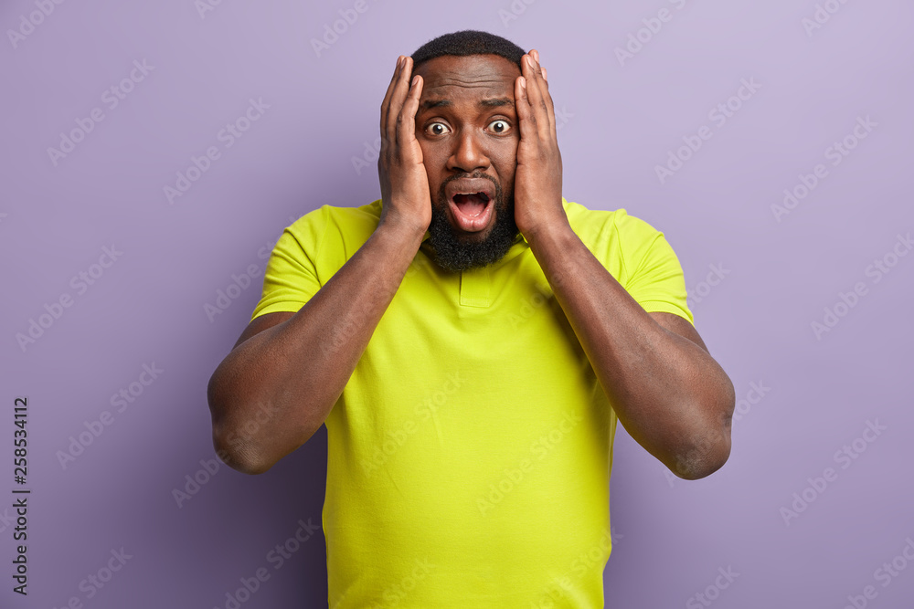 Shocked terrified black bearded man looks in terror, keeps both hands ...