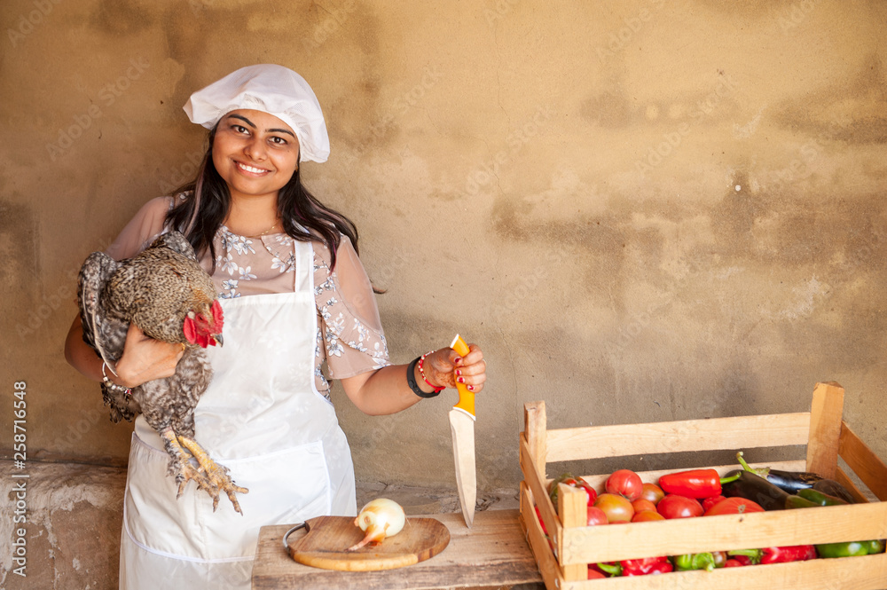 Attractive Indian woman cook posing in kitchen with chicken in her ...