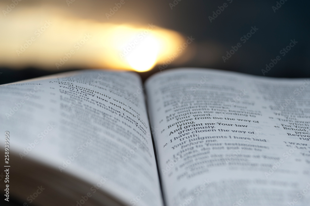 Open Bible with beautiful sunset to the background. Close-up ...
