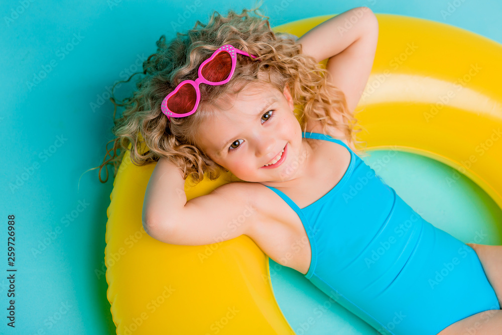 Cute girl in swimsuit holding swimming circle. Isolated on blue ...
