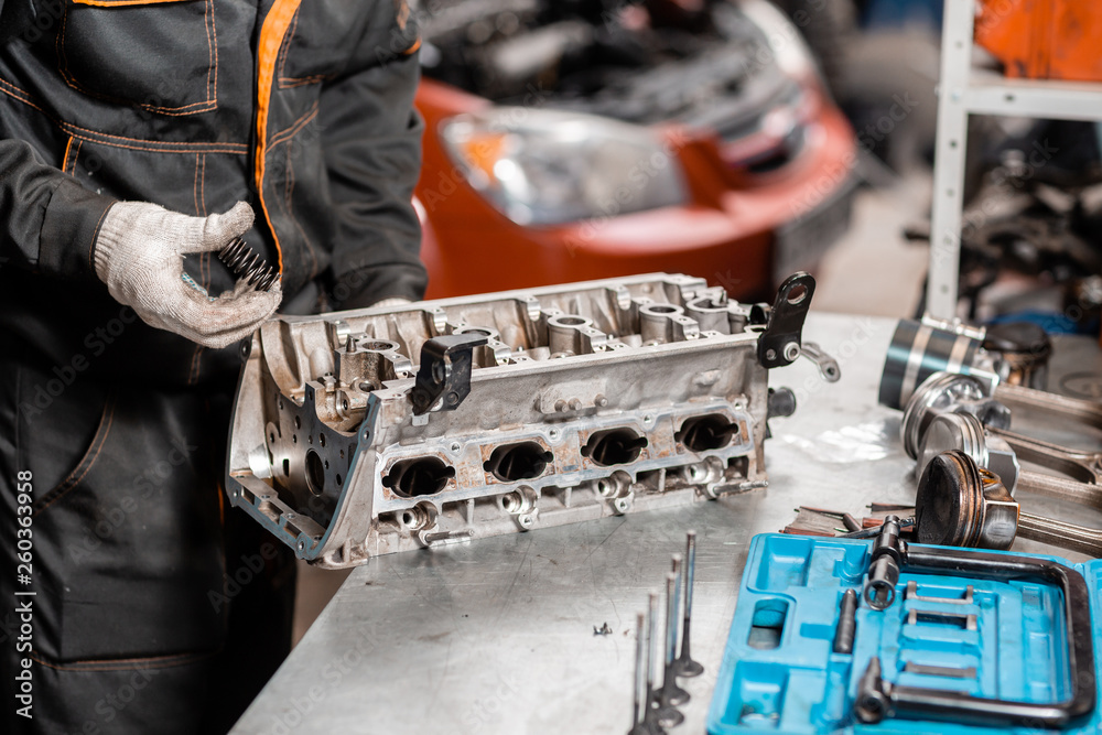 Mechanic disassembling the engine, overhaul.. Engine on a repair stand ...