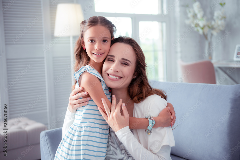 Cute dark-eyed daughter hugging her beaming caring mother の Stock フォト ...