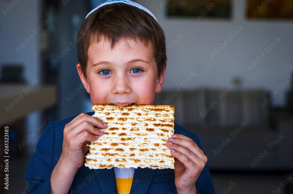 Cute Caucasian Jewish boy holding in his hands and taking a bite from a ...