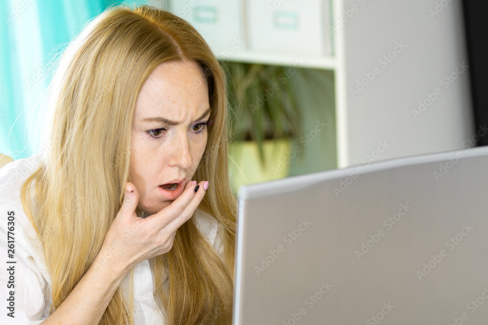 Portrait young shocked business woman sitting in front of laptop computer looking at screen ...