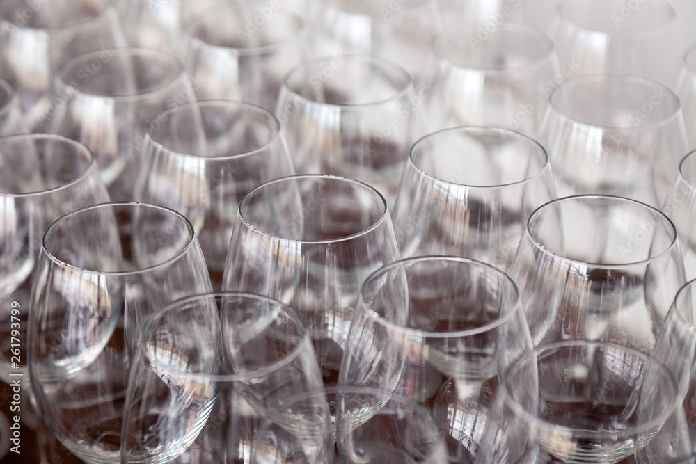Many transparent crystal wine glasses stand in row on the brown wooden ...