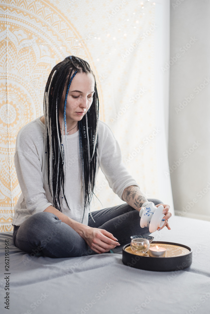 dreadlock girl drinking tea at the ceremony sitting on the sofa with ...