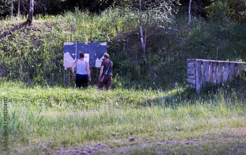 two hunters look at the targets where they hit the bullets; sunny, hot ...