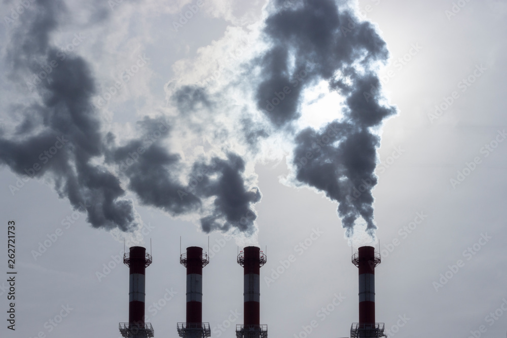 Silhouettes of pipes emitting dark steam into the atmosphere. air ...