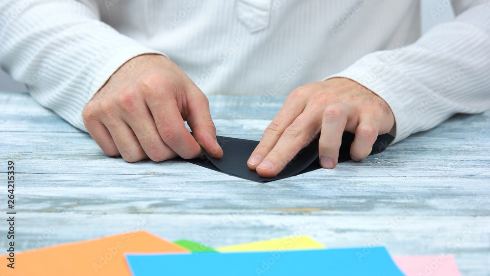 Hands folding black paper sheet. Man making origami close up. How to ...