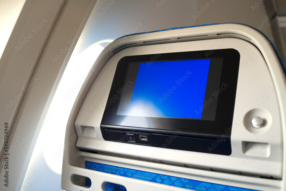 Airplane monitor behind passenger seat with sun light through from the ...