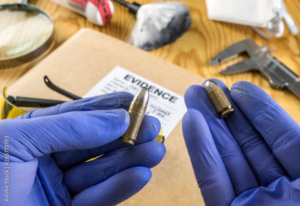Expert police officer comparing two nine millimeters bullets in ...