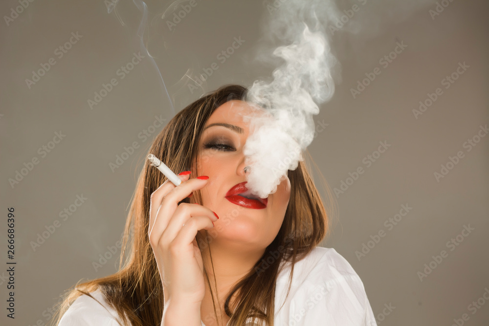 Portrait of beautiful woman with makeup and long hair smoking cigarette ...