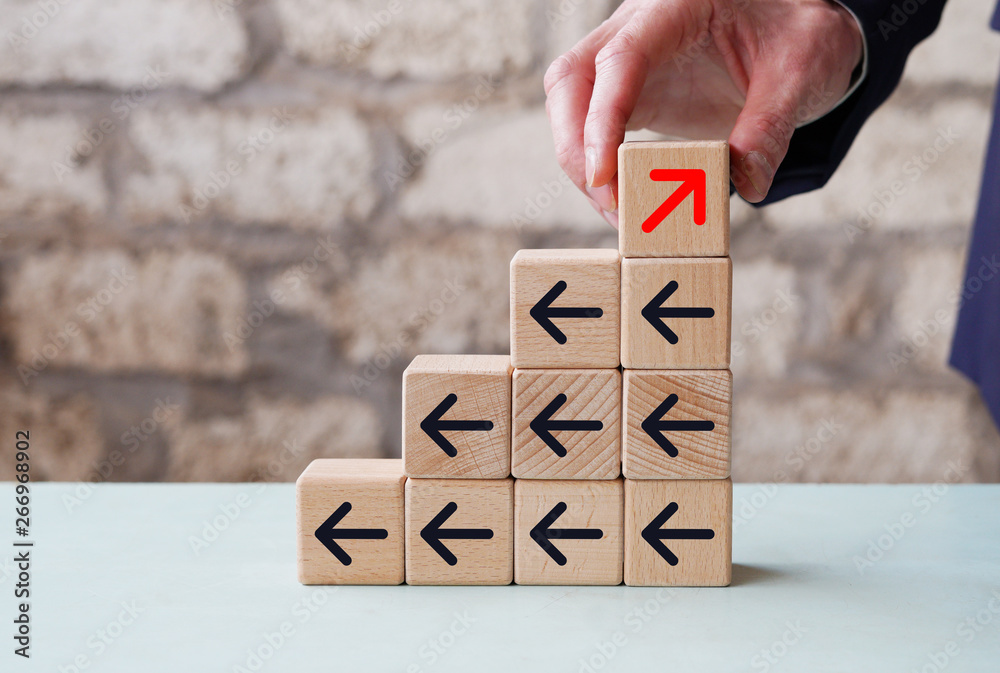 Businessman hand picked wooden block with red arrow facing the opposite ...