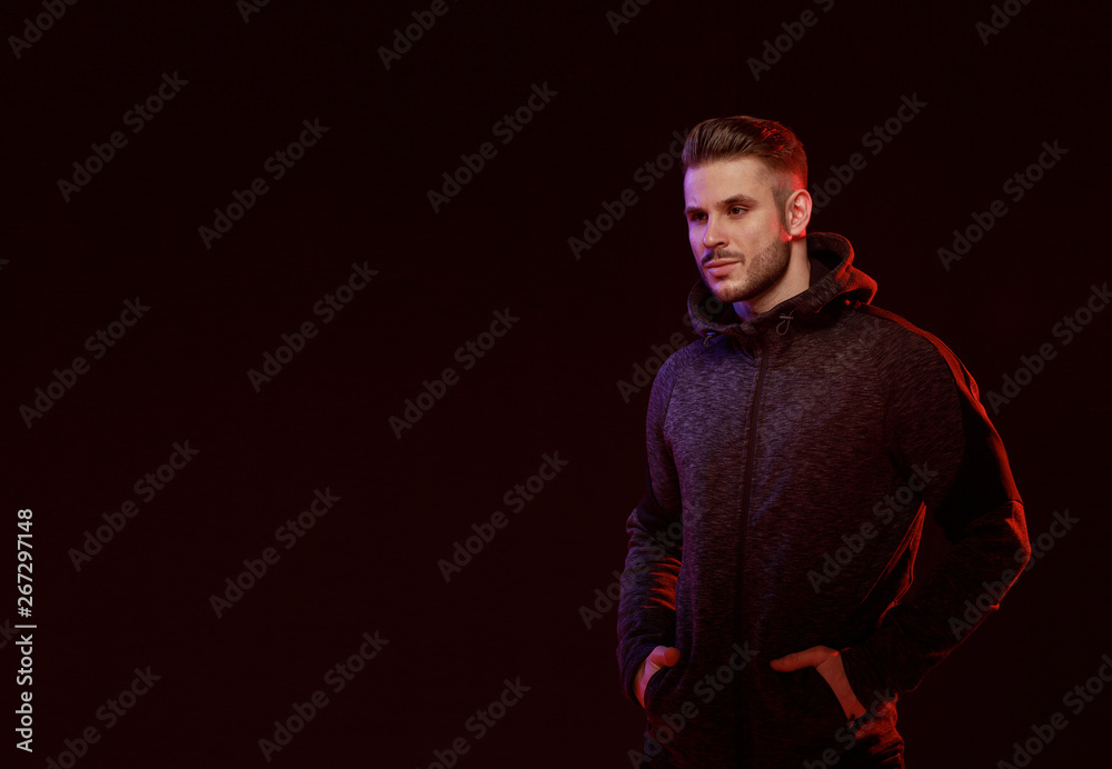 Muscular model young man with beard in black hoody on dark background ...