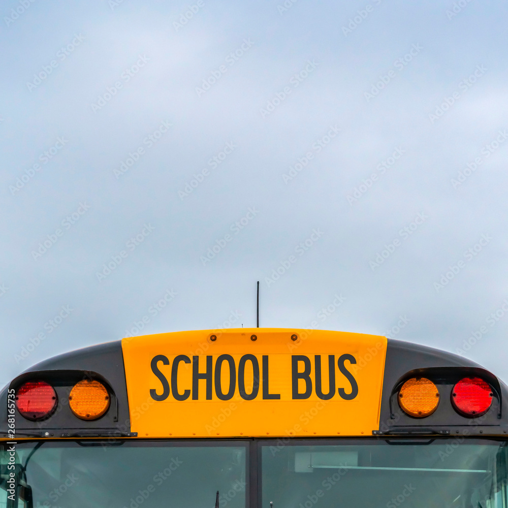 Square Front view of a yellow school bus with homes and cloudy sky in ...