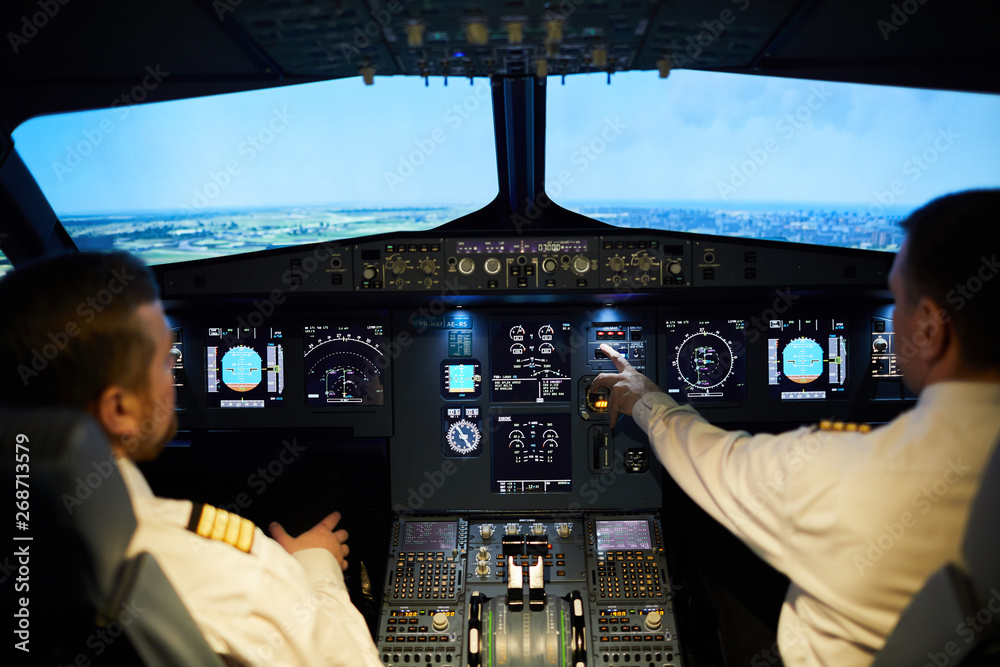 Team of professional pilots sitting at control panel with various ...