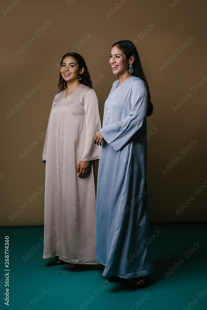 Portrait of two young Middle Eastern Muslim women smiling as they pose ...