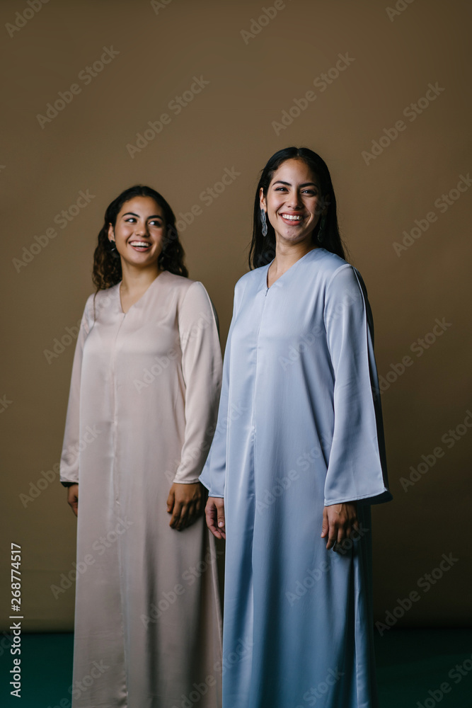 Portrait of two young Middle Eastern Muslim women smiling as they pose ...