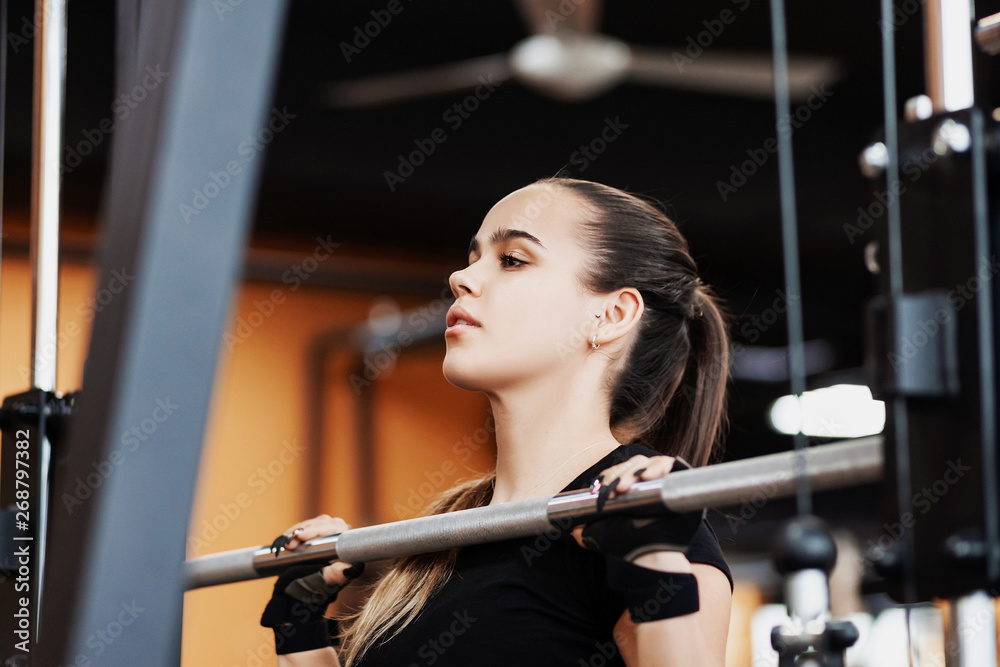 strong-willed young girl fitness model engaged with a barbell in the ...