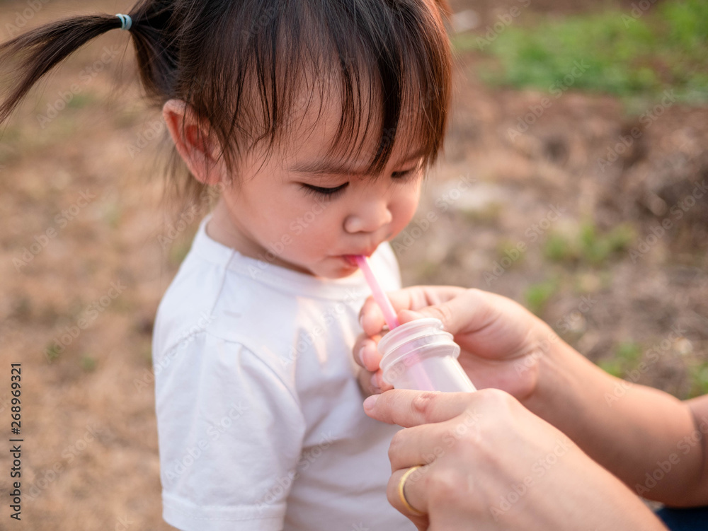 Asian little child girl drink water from tube after tired of playing in ...