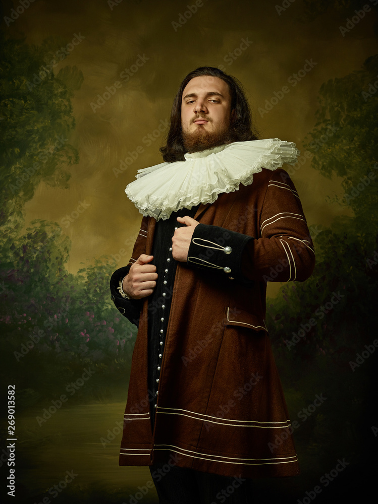 Young man as a medieval knight on dark studio background. Portrait in ...