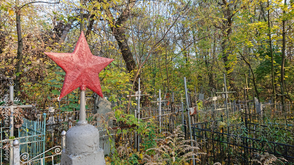 An old cemetery, a gravestone with a red star on the grave of a ...