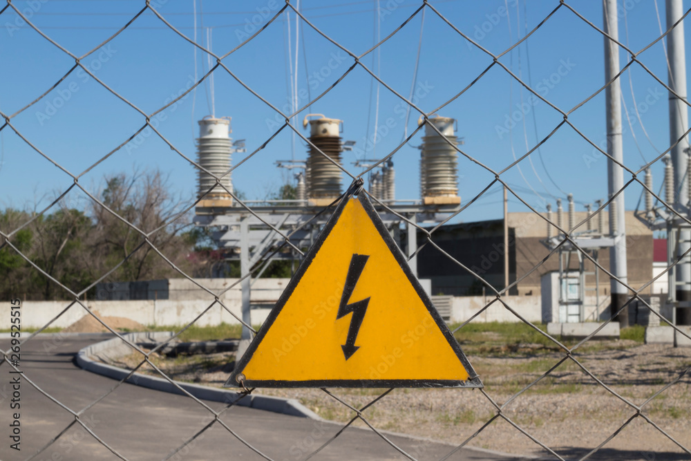 Electrical hazard sign on metal grid. On the background of unfocused ...