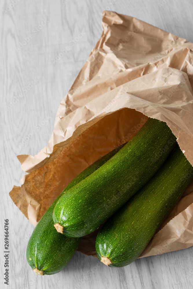 Organic courgette in a brown paper bag on grey wood. Recycle packaging ...