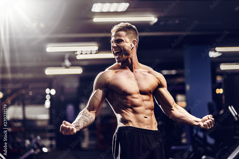 Side view of a caucasian handsome fitness model posing in the gym. Man ...