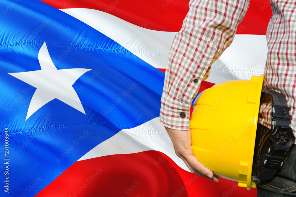 Engineer is holding yellow safety helmet with waving Puerto Rico flag ...