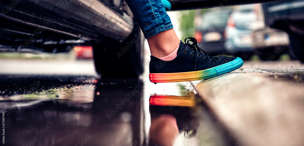 Girl stepping out of the car and avoiding puddle Stock Photo | Adobe Stock