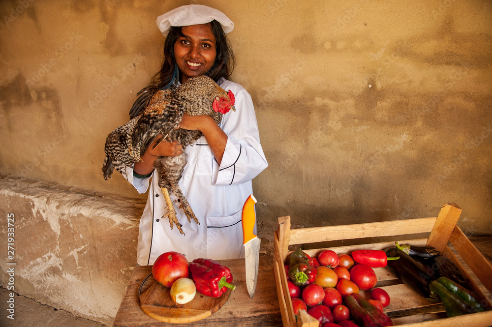 Attractive Indian woman cook posing in kitchen with chicken in her ...