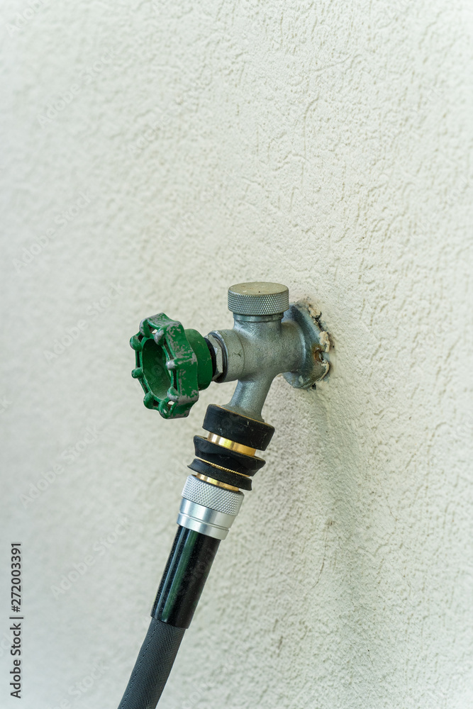 outdoor hose bib water connection on outside of stucco wall of house ...